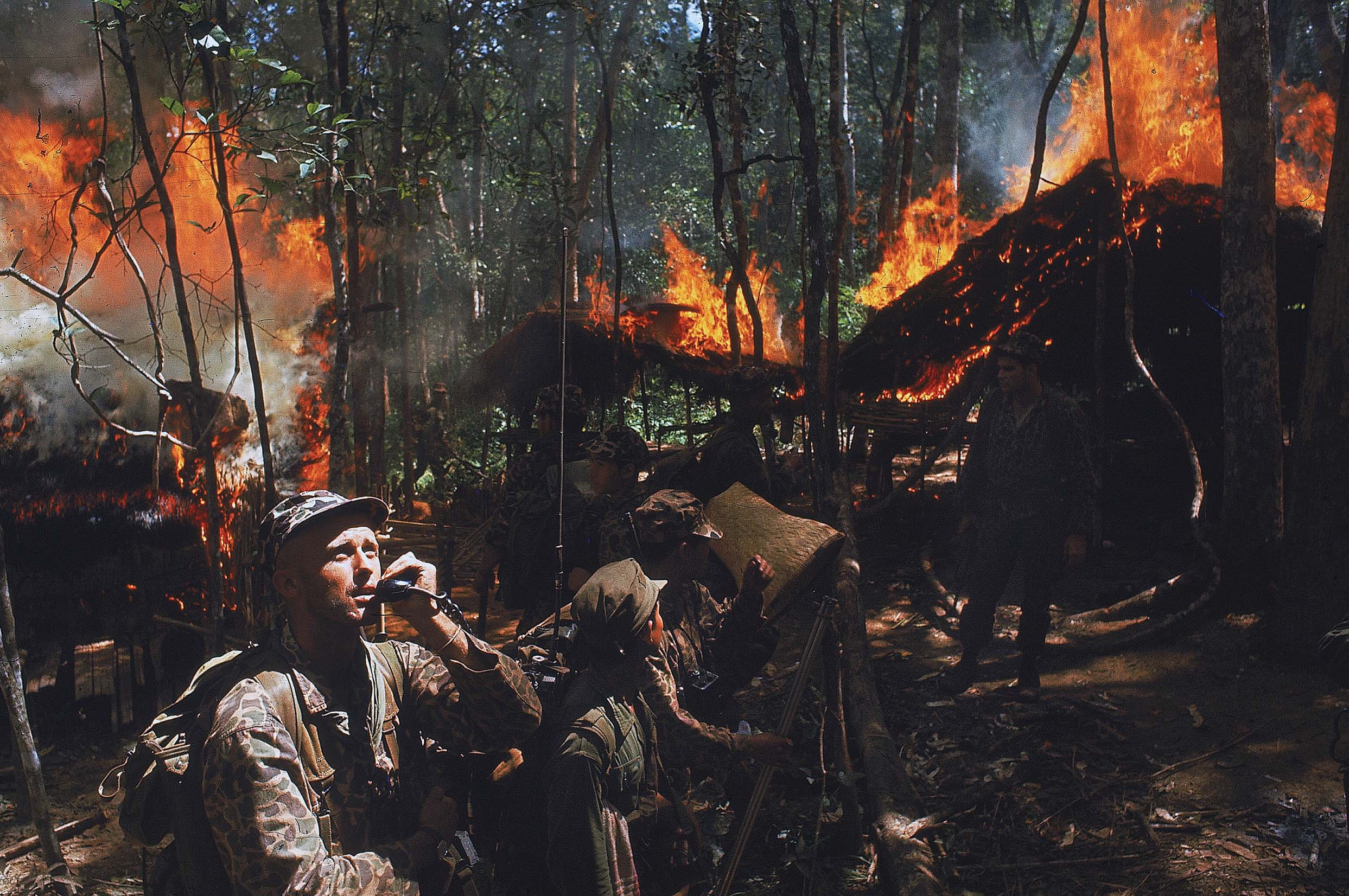 Gillespie contacts his base camp while South Vietnamese soldiers burn a ...